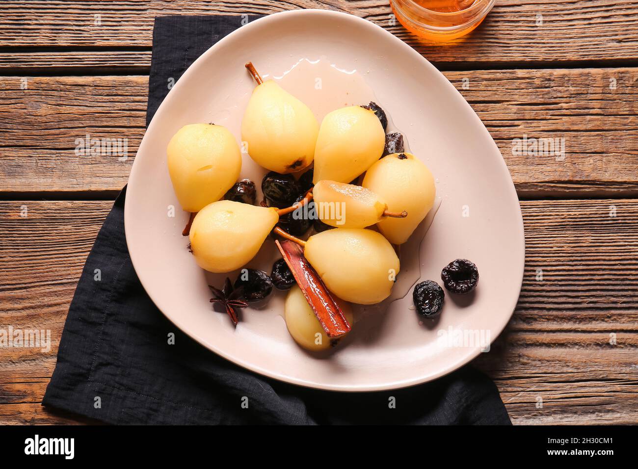 Dish with delicious poached pears, prunes, anise and cinnamon on wooden ...