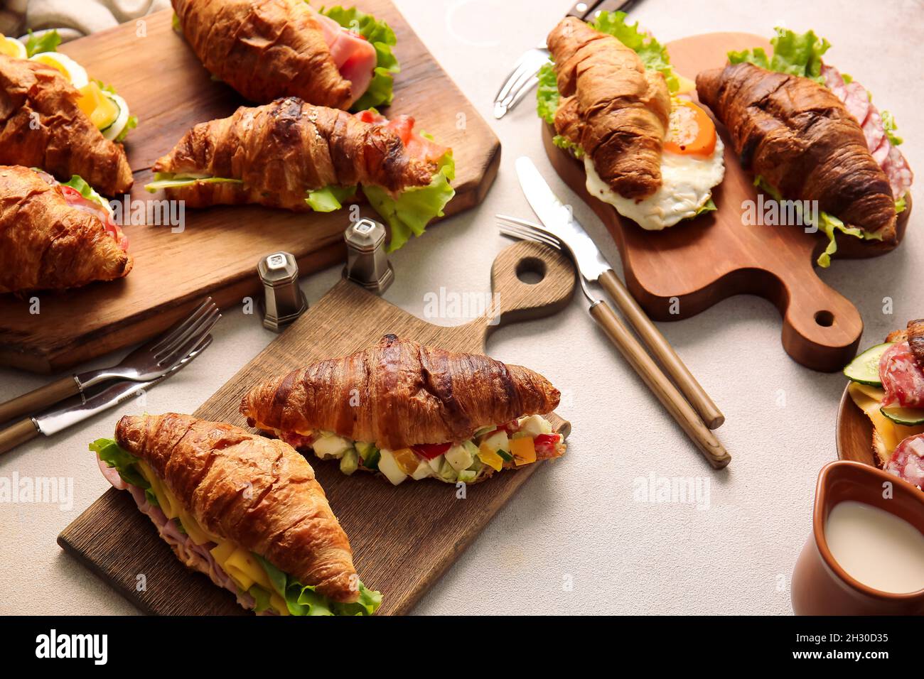 Wooden boards with delicious croissant sandwiches on white background ...