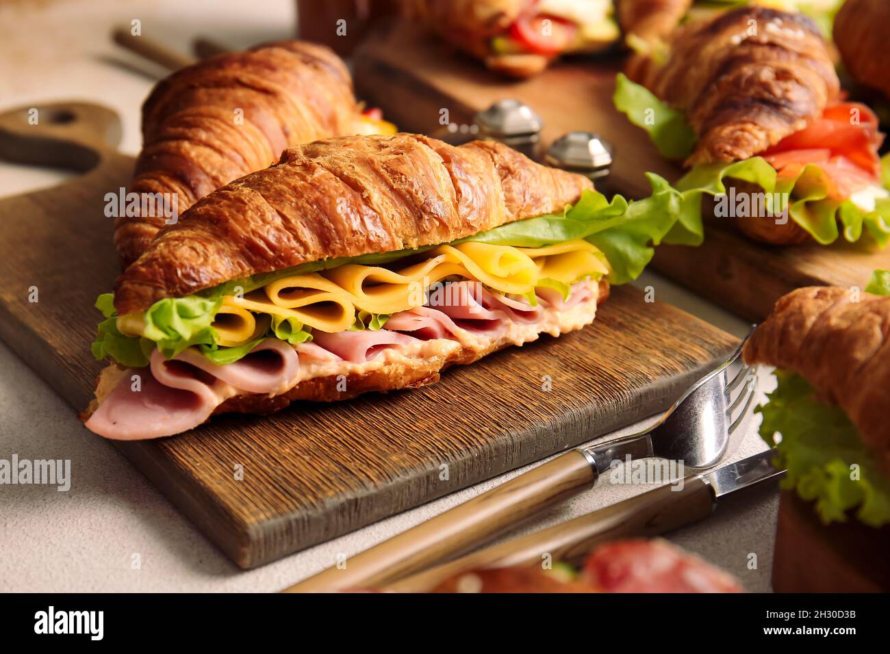 Wooden boards with delicious croissant sandwiches on white background ...