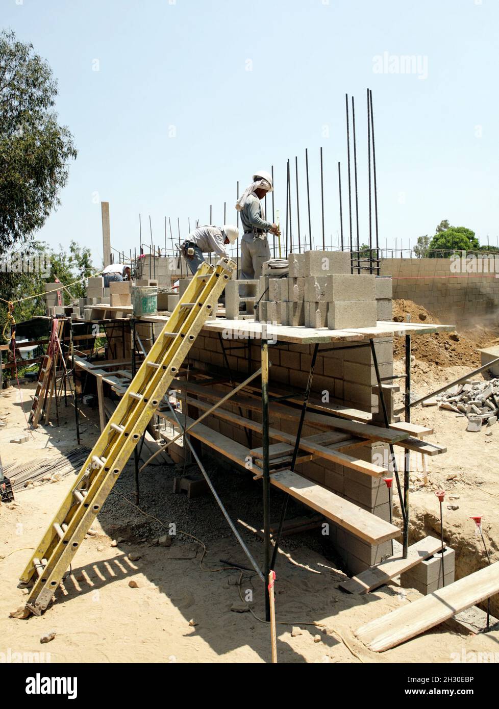 Concrete Masons building a block wall on scaffolding Stock Photo - Alamy