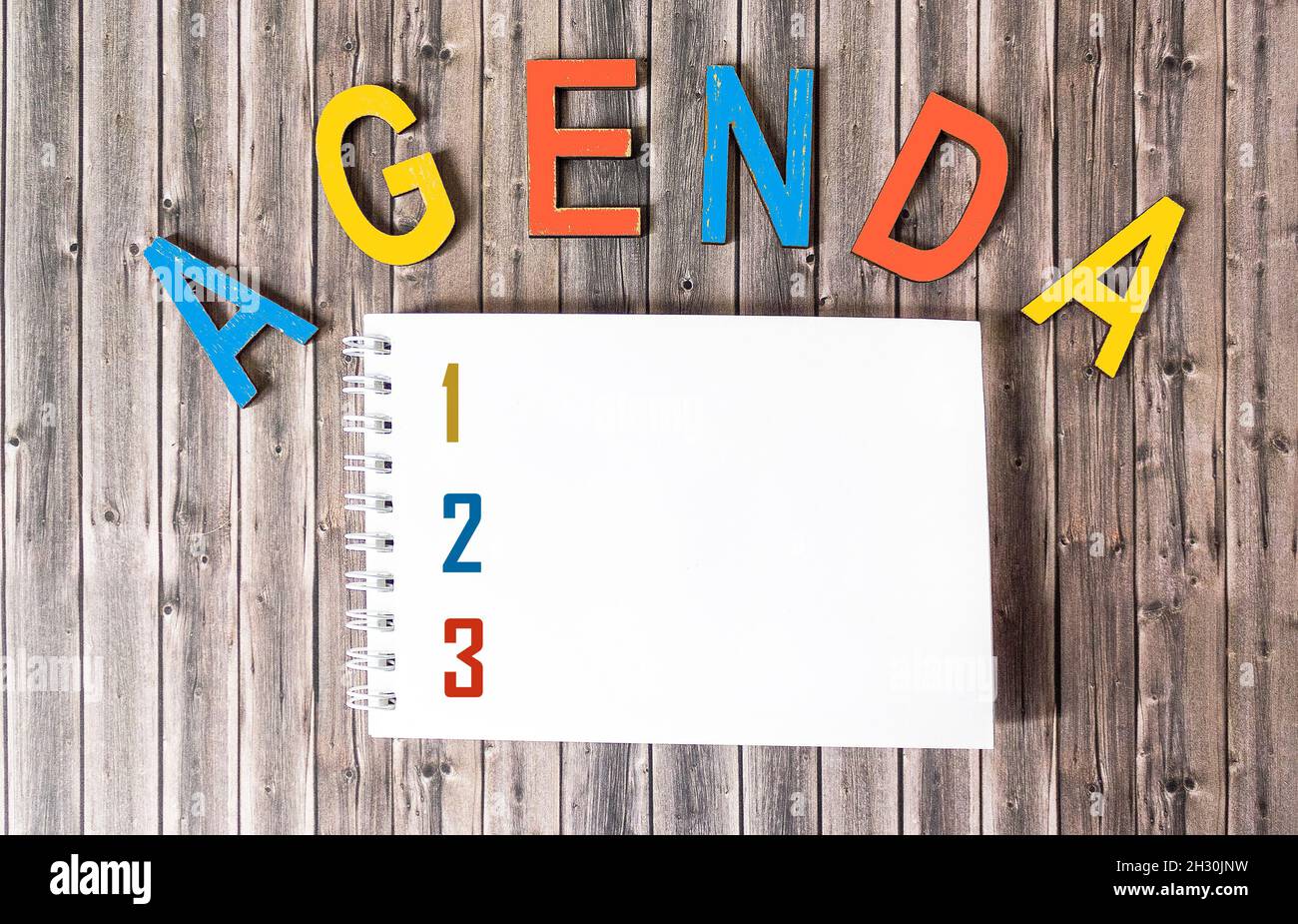 Agenda word made from wooden letters, next to notepad with place to ...