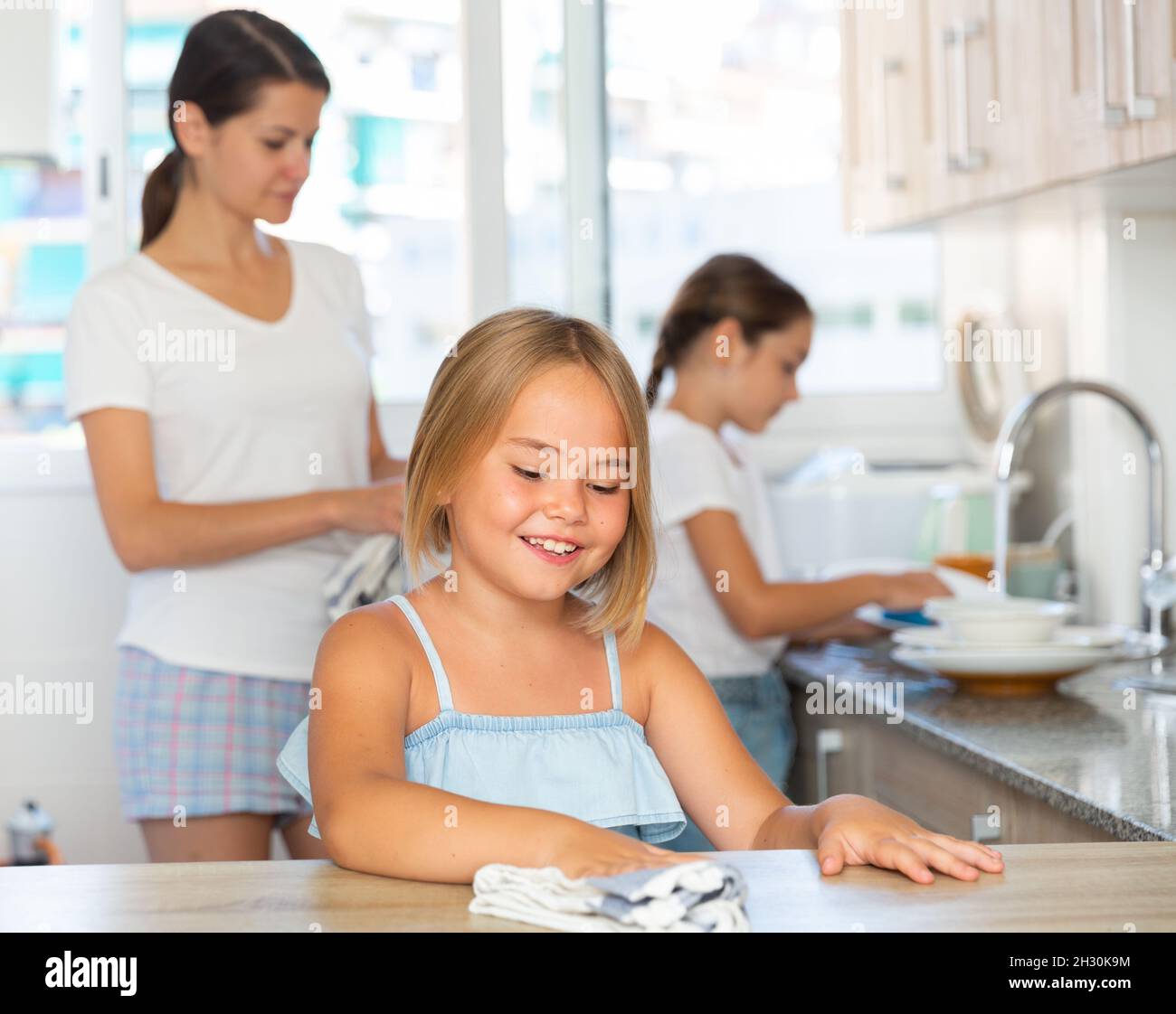 Family working at kitchen, girl cleaning table Stock Photo - Alamy