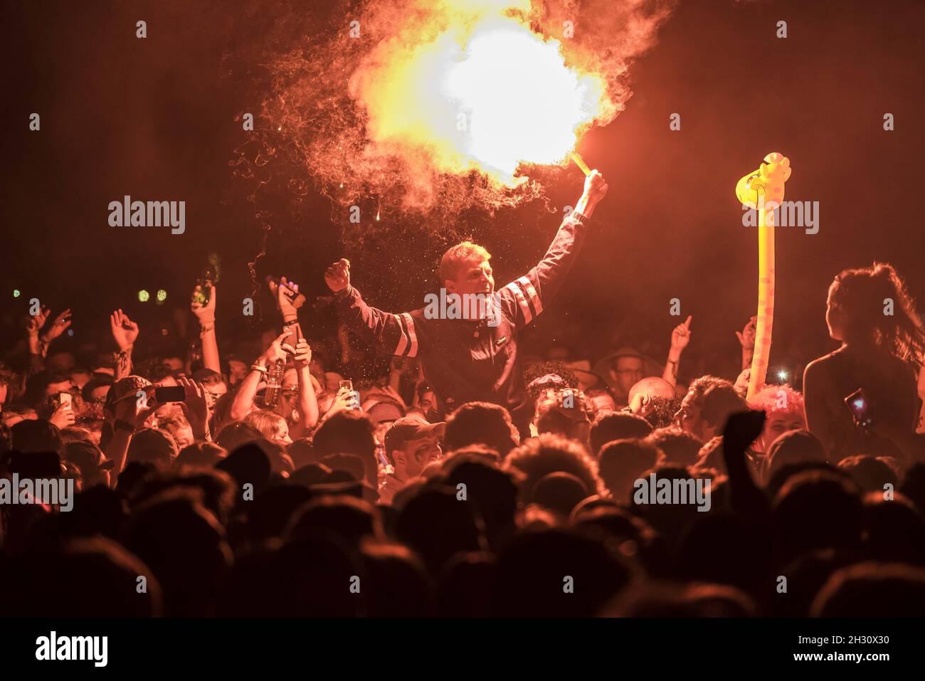 Festival goer holding a flare in the main stage crowd on day 3 of ...