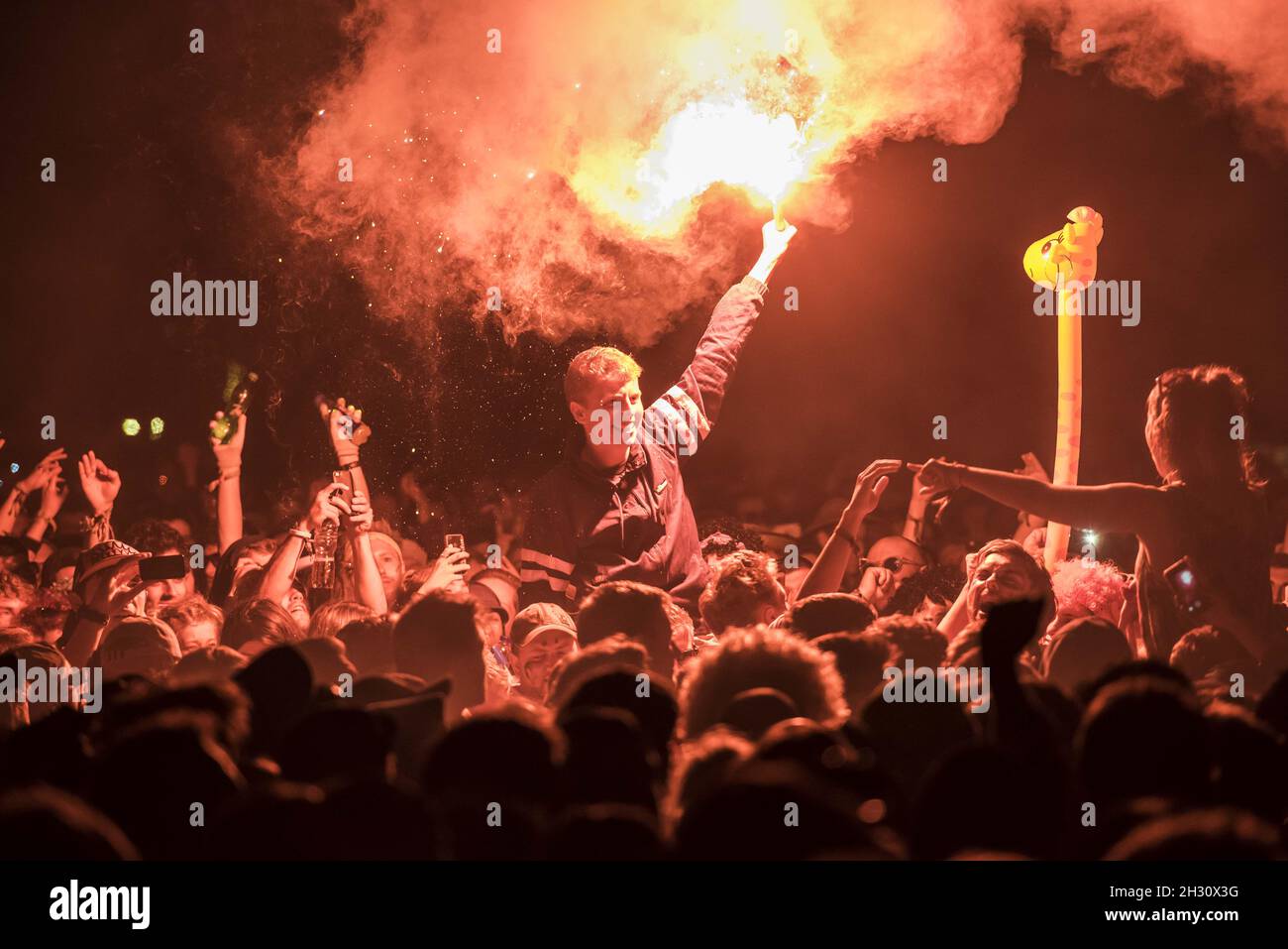 Festival goer holding a flare in the main stage crowd on day 3 of ...