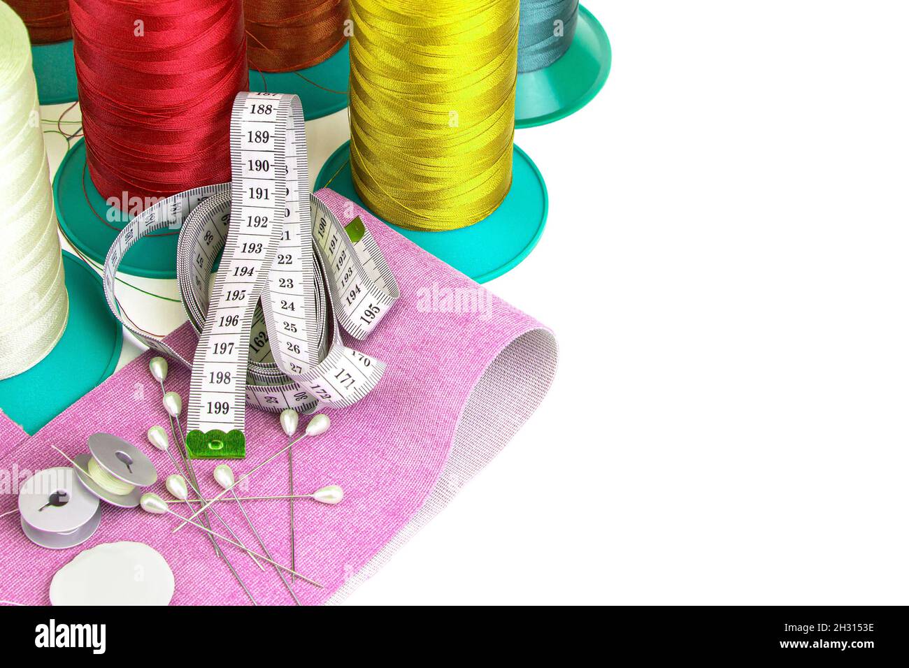 Sewing on a white background, reels with threads, needles and pieces of ...