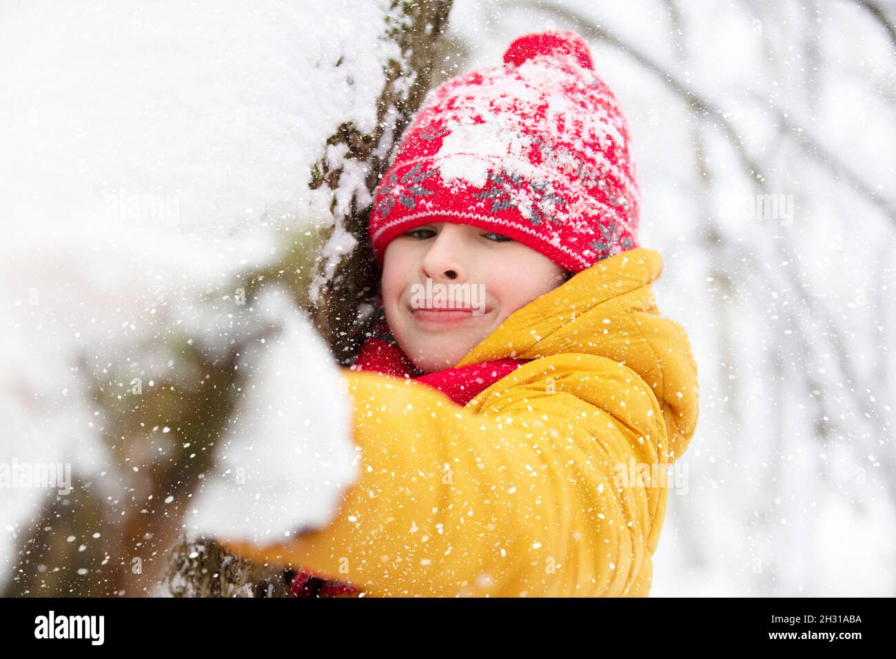 Funny little boy in colorful clothes playing outdoors during a snowfall ...
