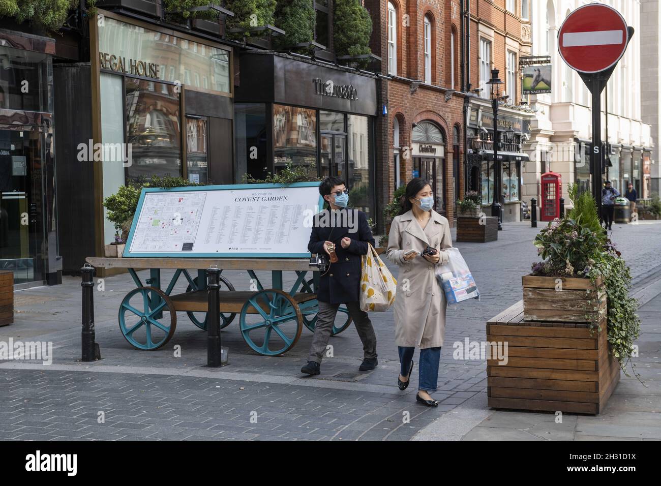 A couple wearing protective masks walk past Covent Garden Underground ...