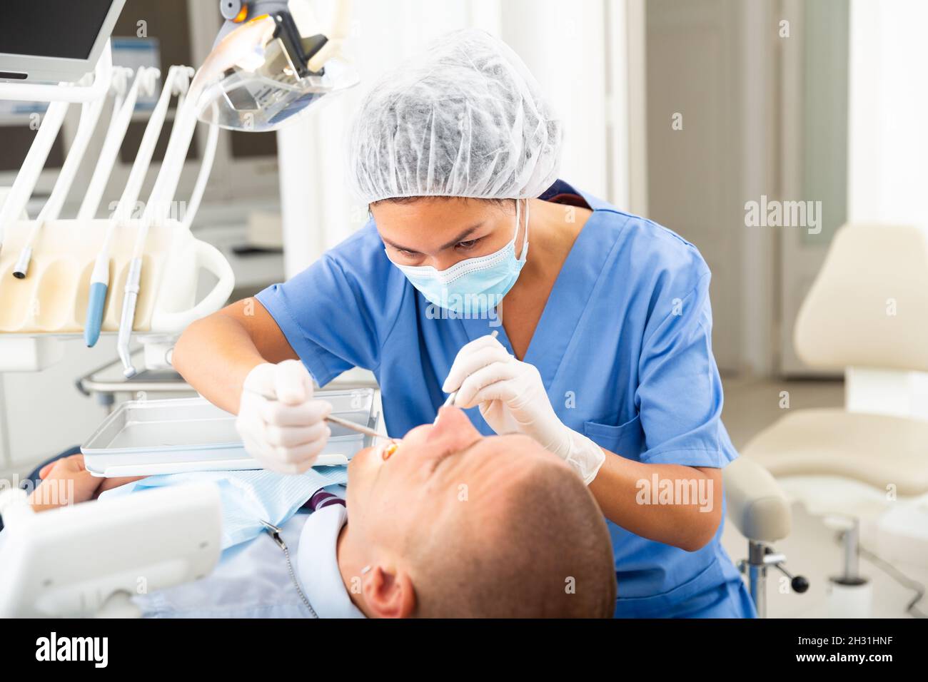 Dentist professional filling teeth for man patient sitting in chair Stock Photo - Alamy
