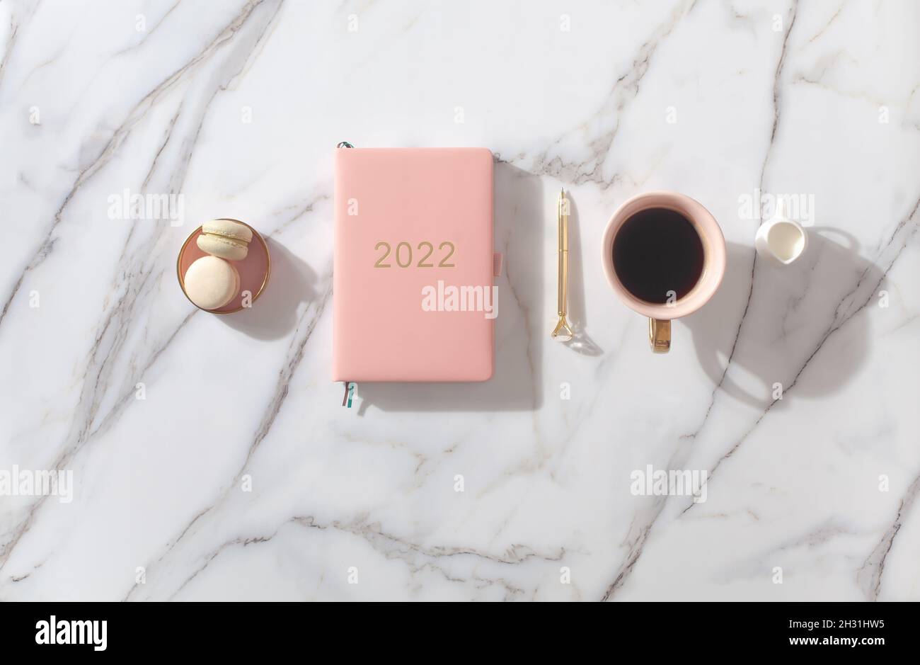 Pink coral colored diary for the year 2022, pen, coffee, macaron cookie ...