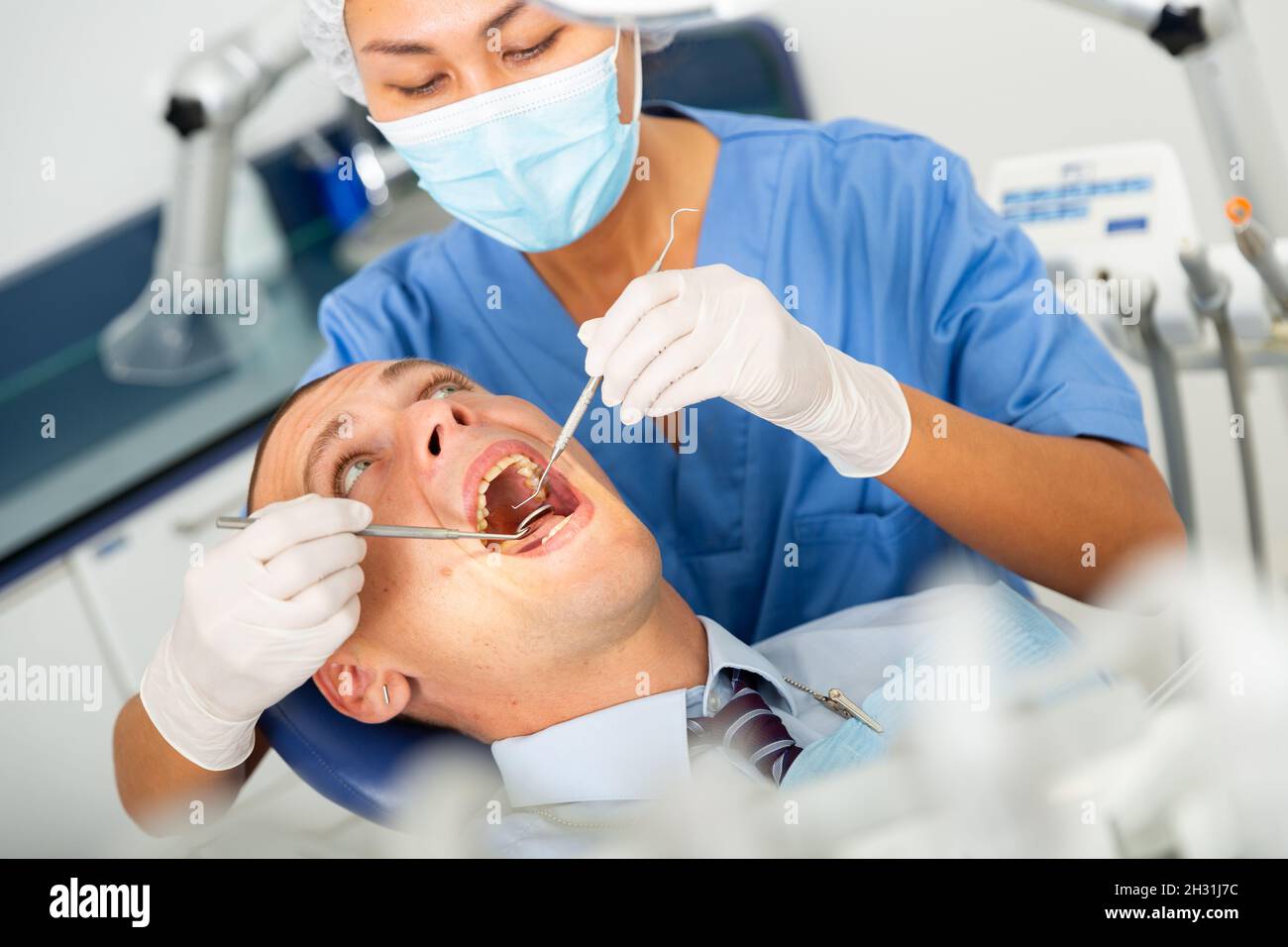 Doctor in uniform is examinating man on chair in hospital Stock Photo ...