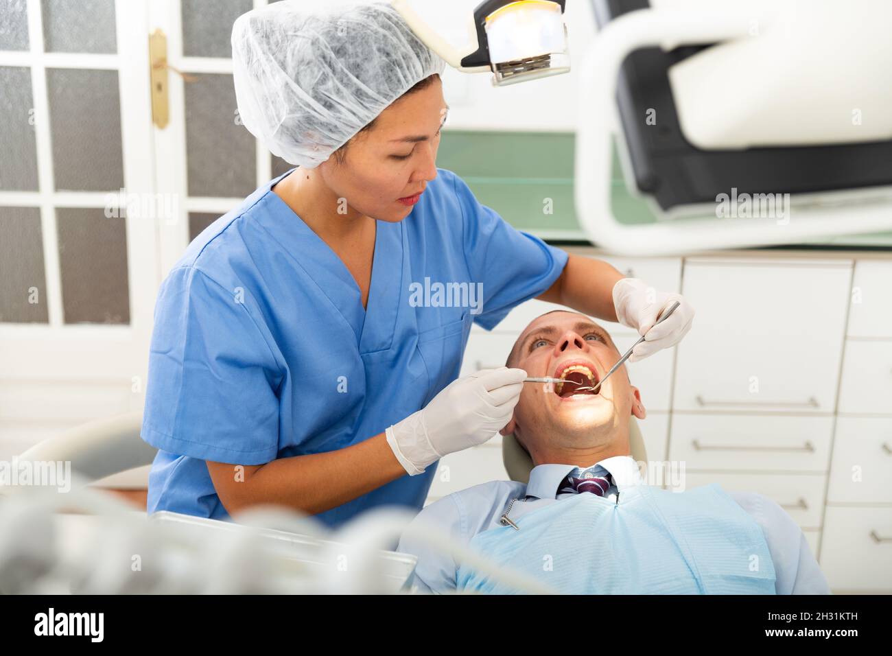 Dentist inspects male patient teeth Stock Photo - Alamy