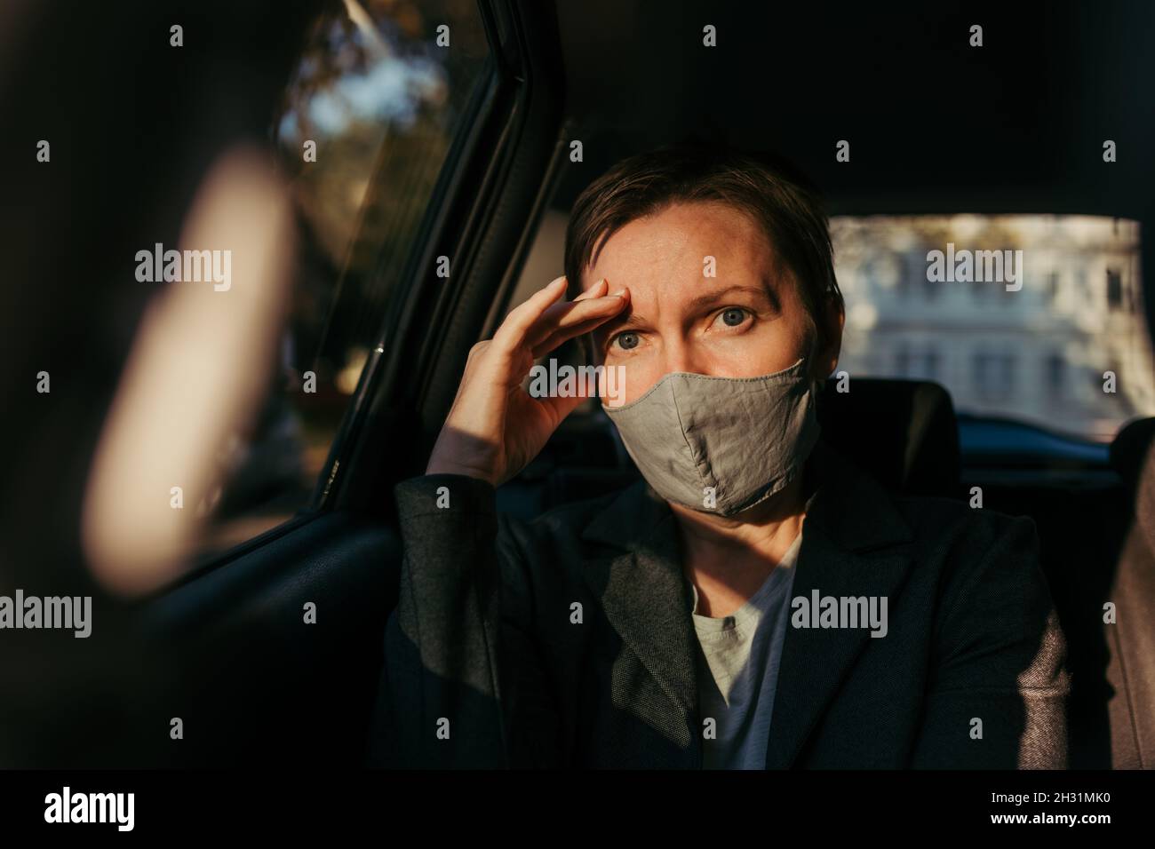 Anxious businesswoman sitting inside of the car and looking at camera ...