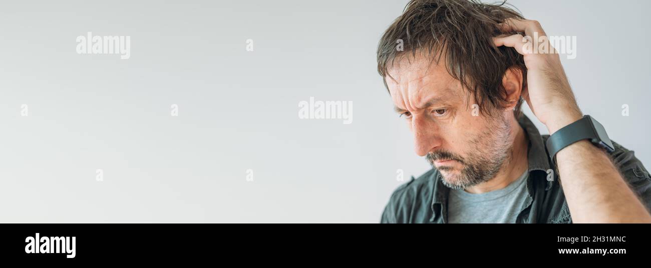 Forgetfulness concept, guy scratching his head trying to remember ...