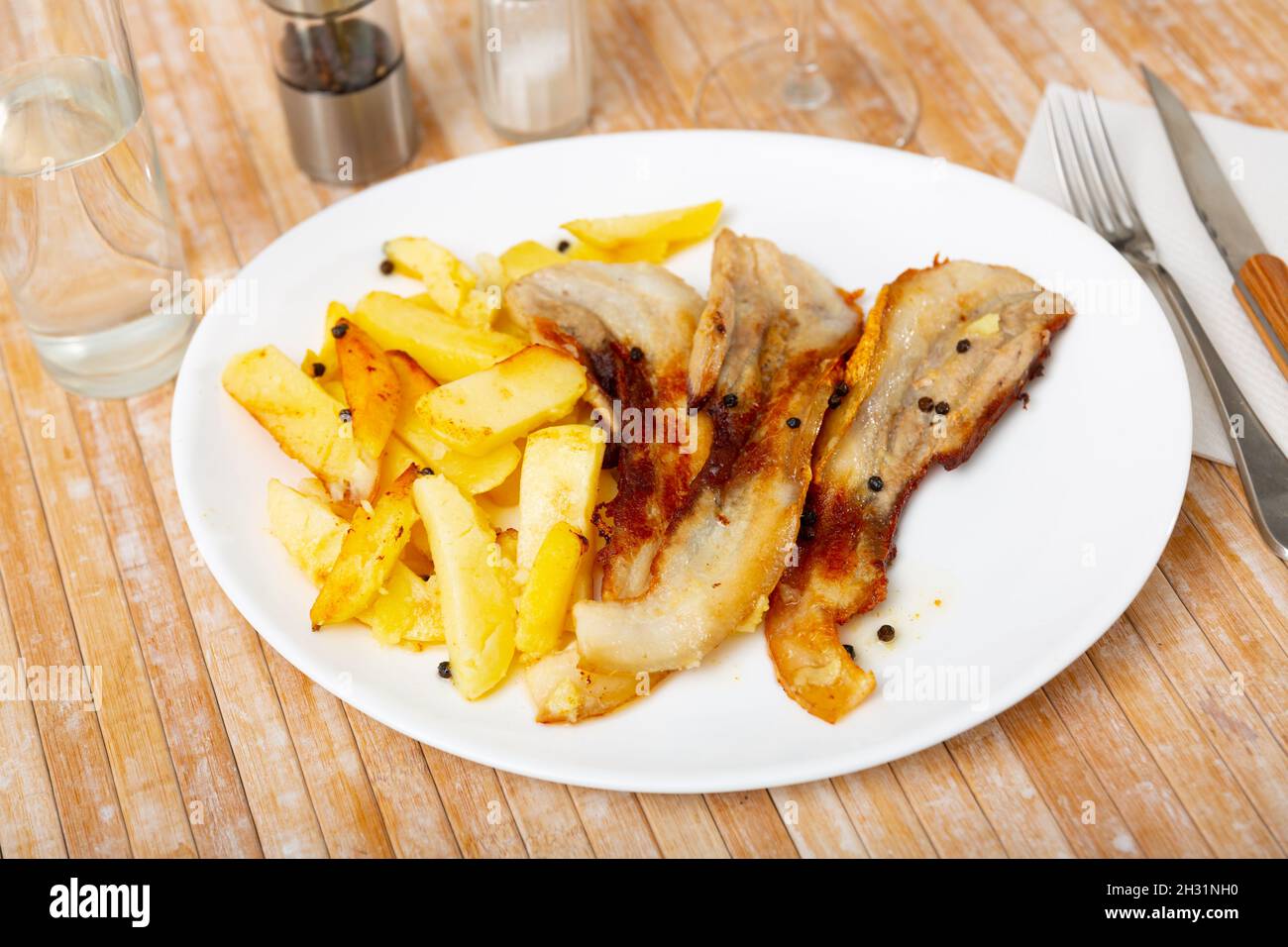 Fried potatoes and roasted streaky pork belly strips Stock Photo - Alamy