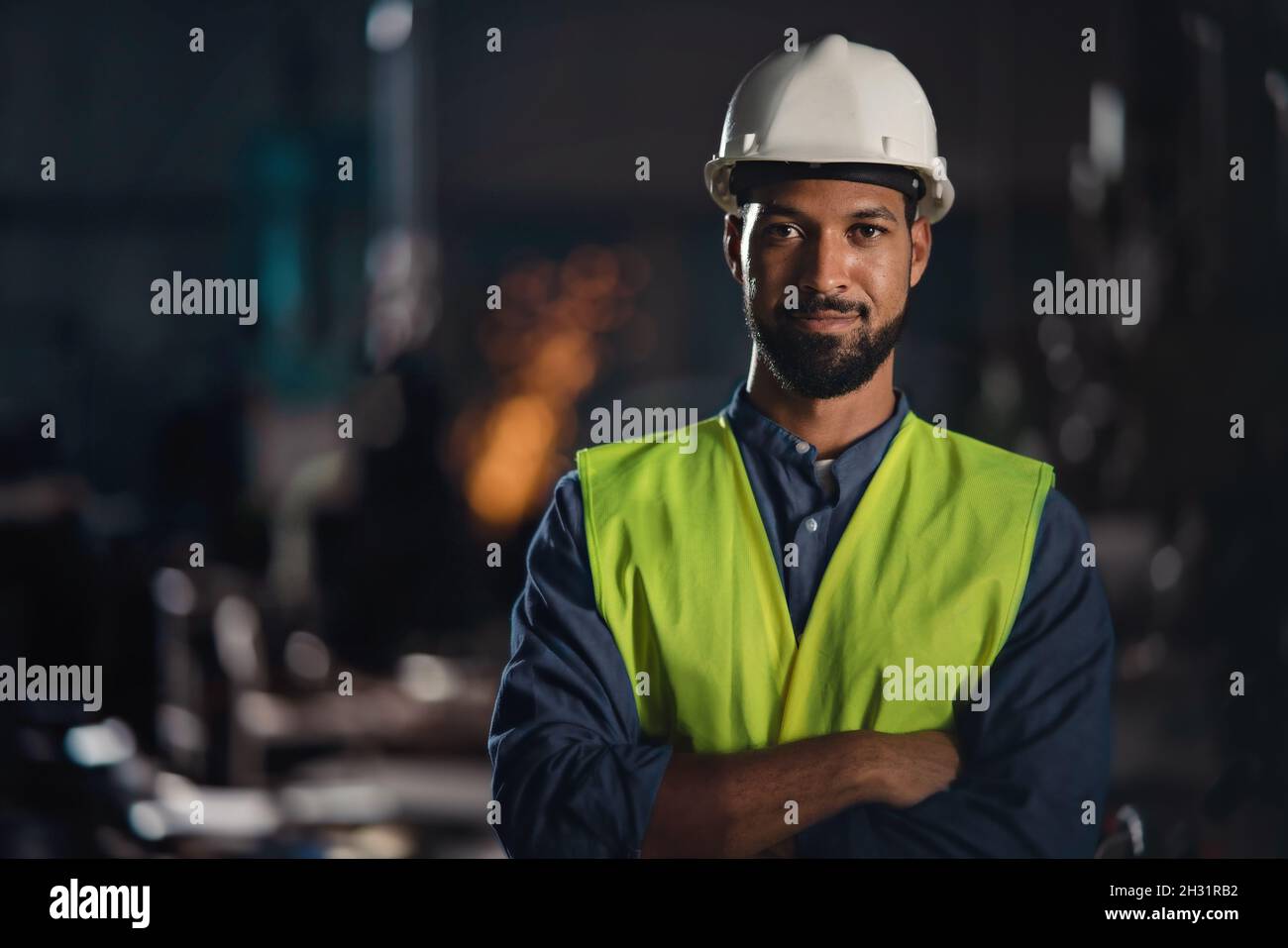 Portrait of happy young industrial man with protective wear indoors in ...