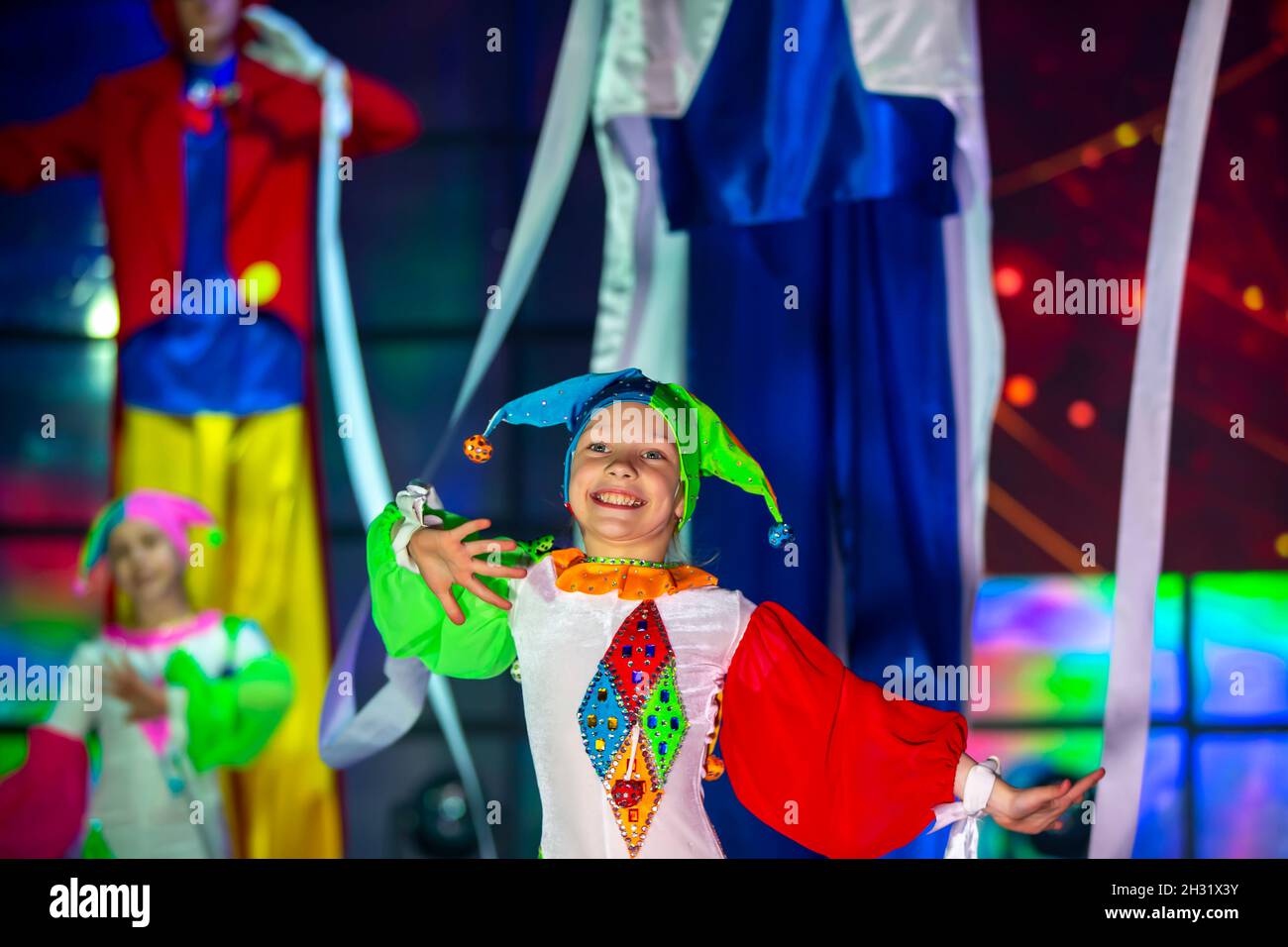 Little girl is dancing in a clown costume. The child performs on stage ...