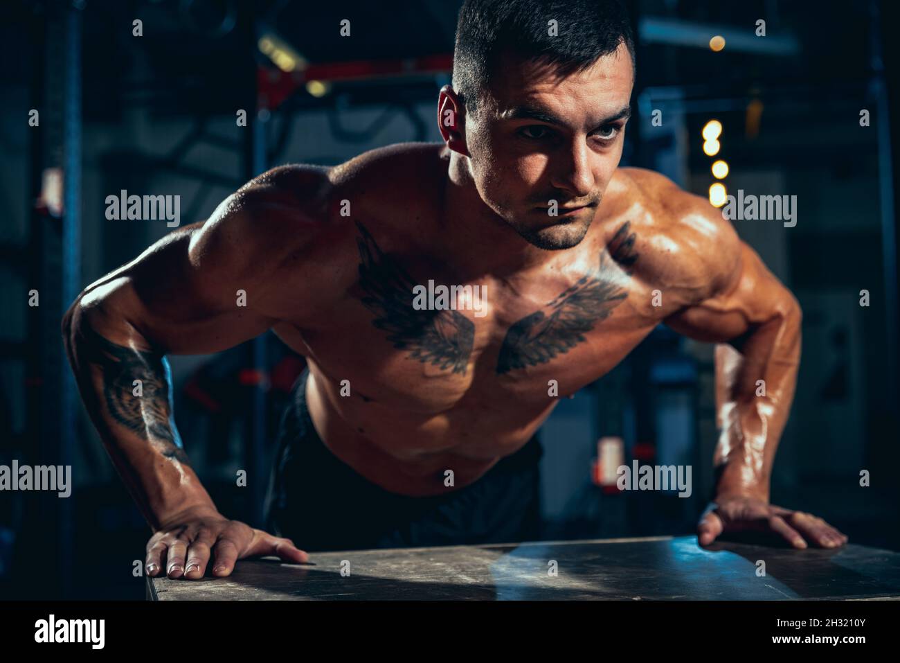 Close-up young man, muscled athlete, bodybuilder push-ups at sport gym ...