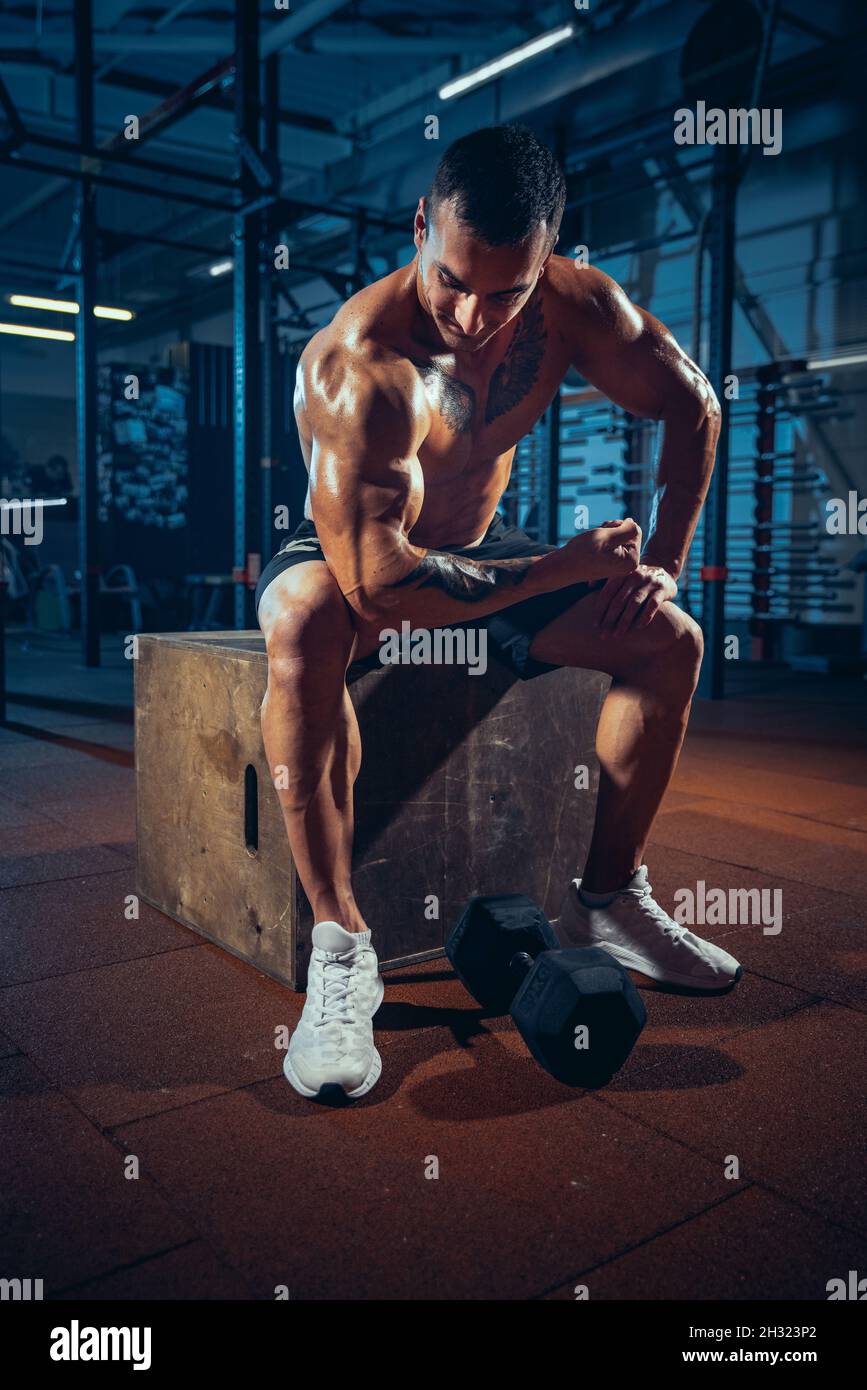 Image of young man, bodybuilder training with dumbbells at modern sport ...