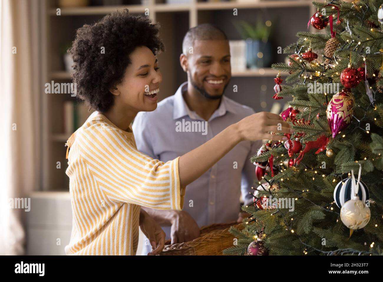 Happy mixed race family couple decorating Christmas tree Stock Photo ...