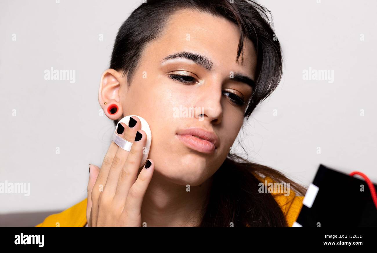Transgender woman applying makeup foundation at home. Daily life Stock ...