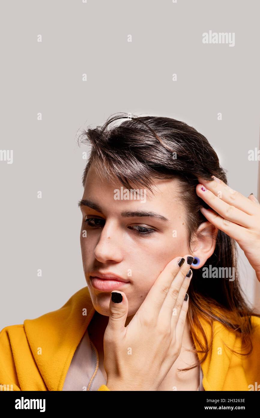 Transgender woman applying makeup foundation at home. Daily life Stock ...