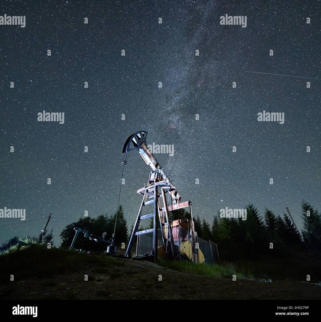 Low view of active oil well at night under beautiful starry sky. Oil ...