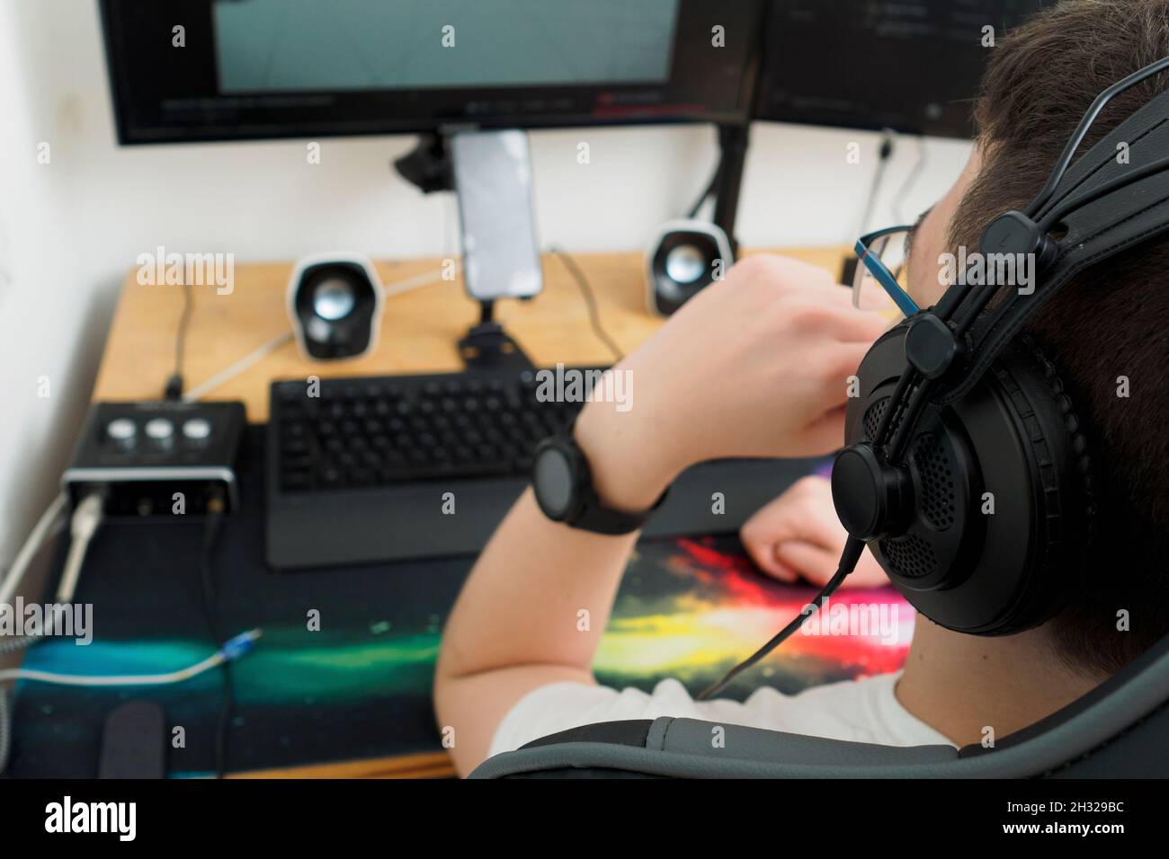 A young gamer with headphones boy playing a computer game on a powerful ...