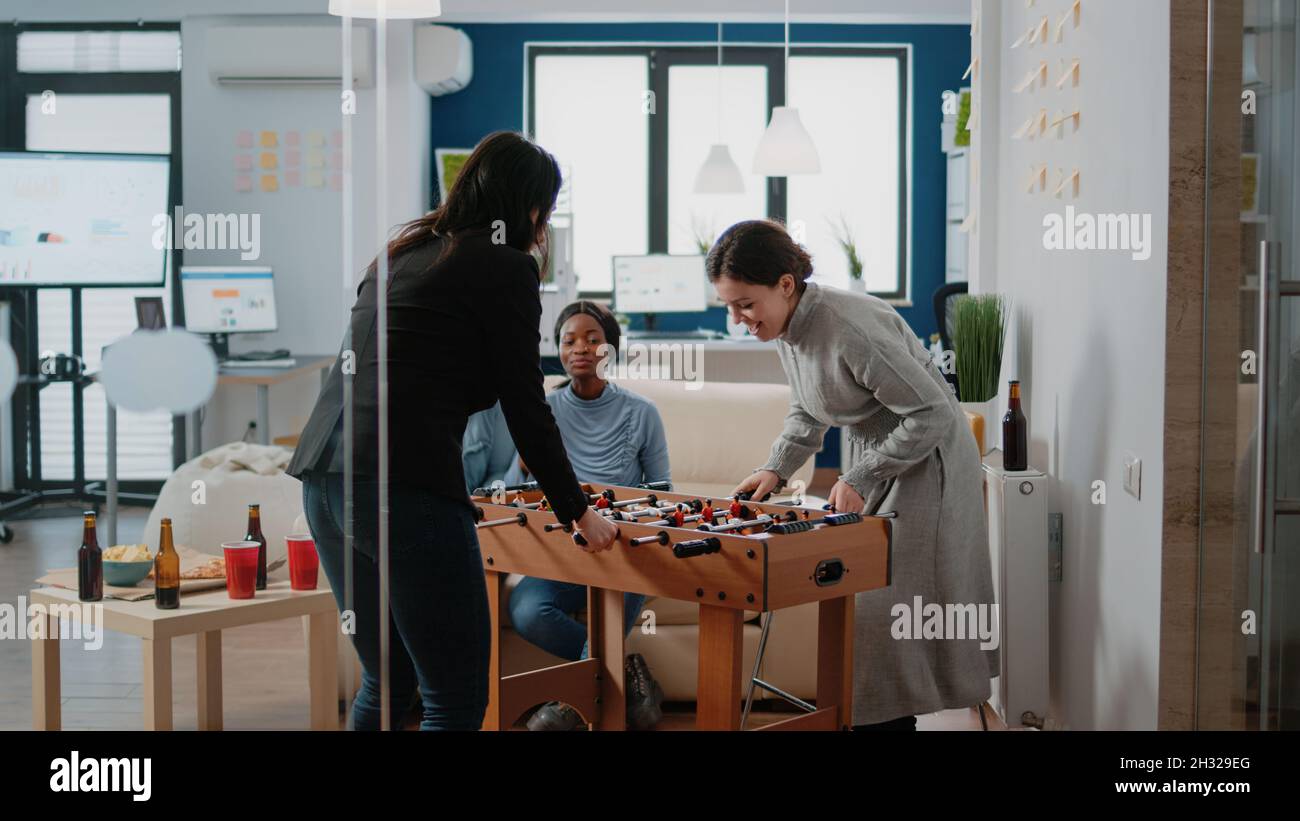 Businesspeople playing foosball game at table to do fun activity after ...