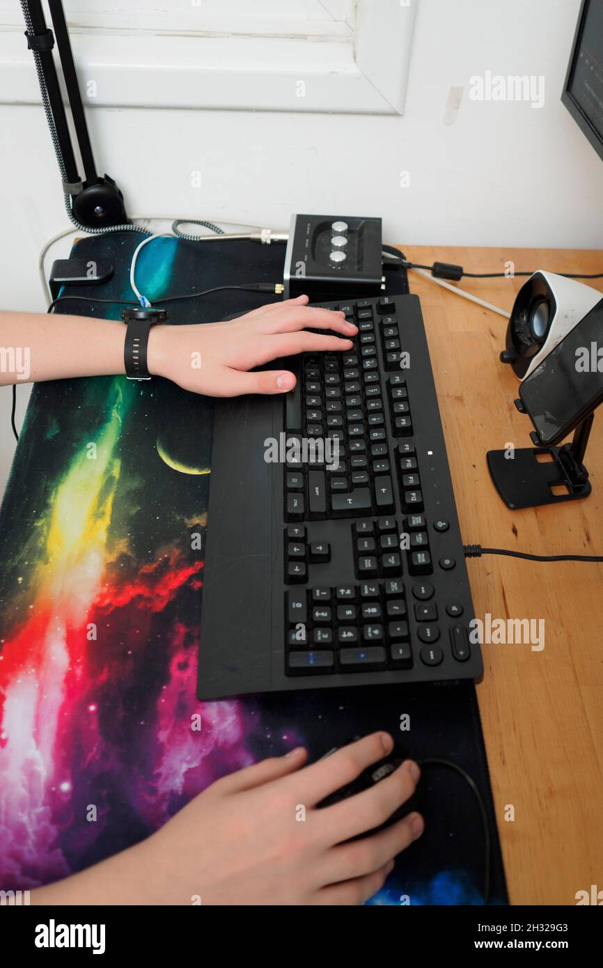 A young gamer with headphones boy playing a computer game on a powerful ...