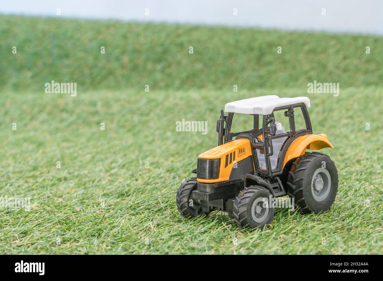Small toy tractor standing in 'field' of faux / fake grass. For UK food ...