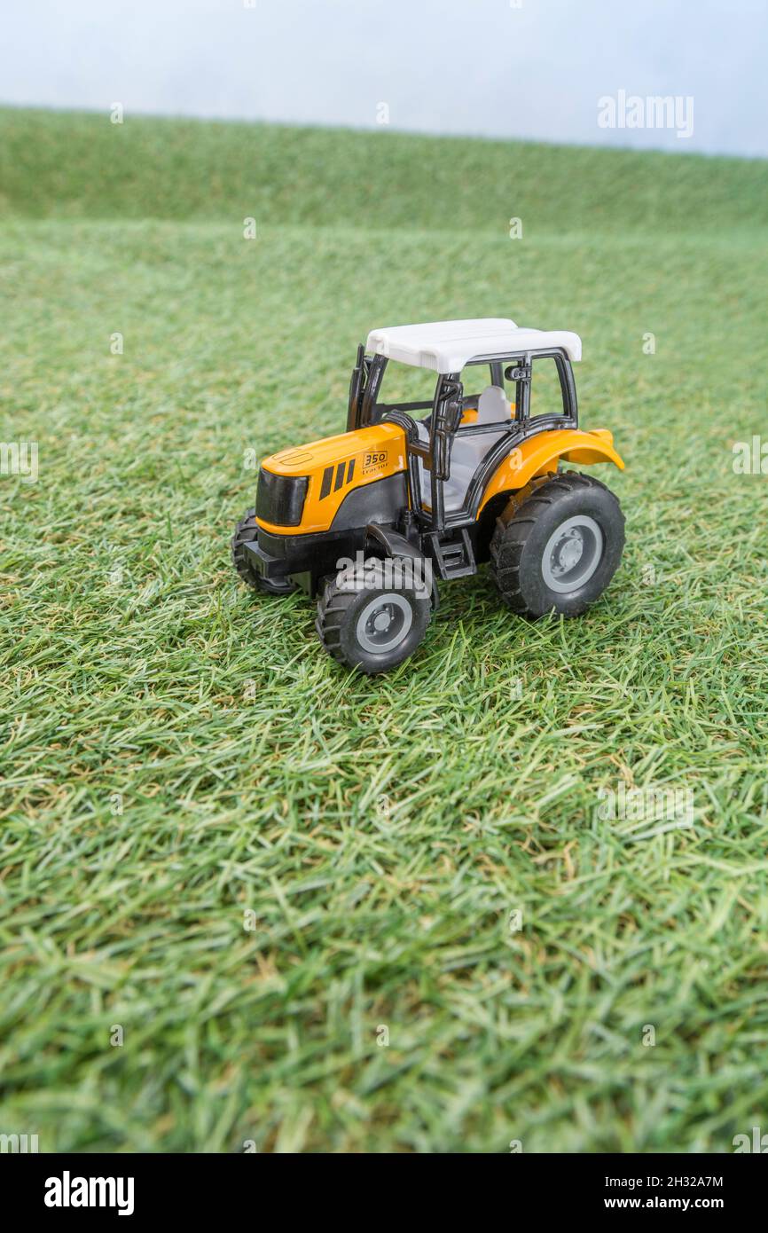 Small toy tractor standing in 'field' of faux / fake grass. For UK food ...