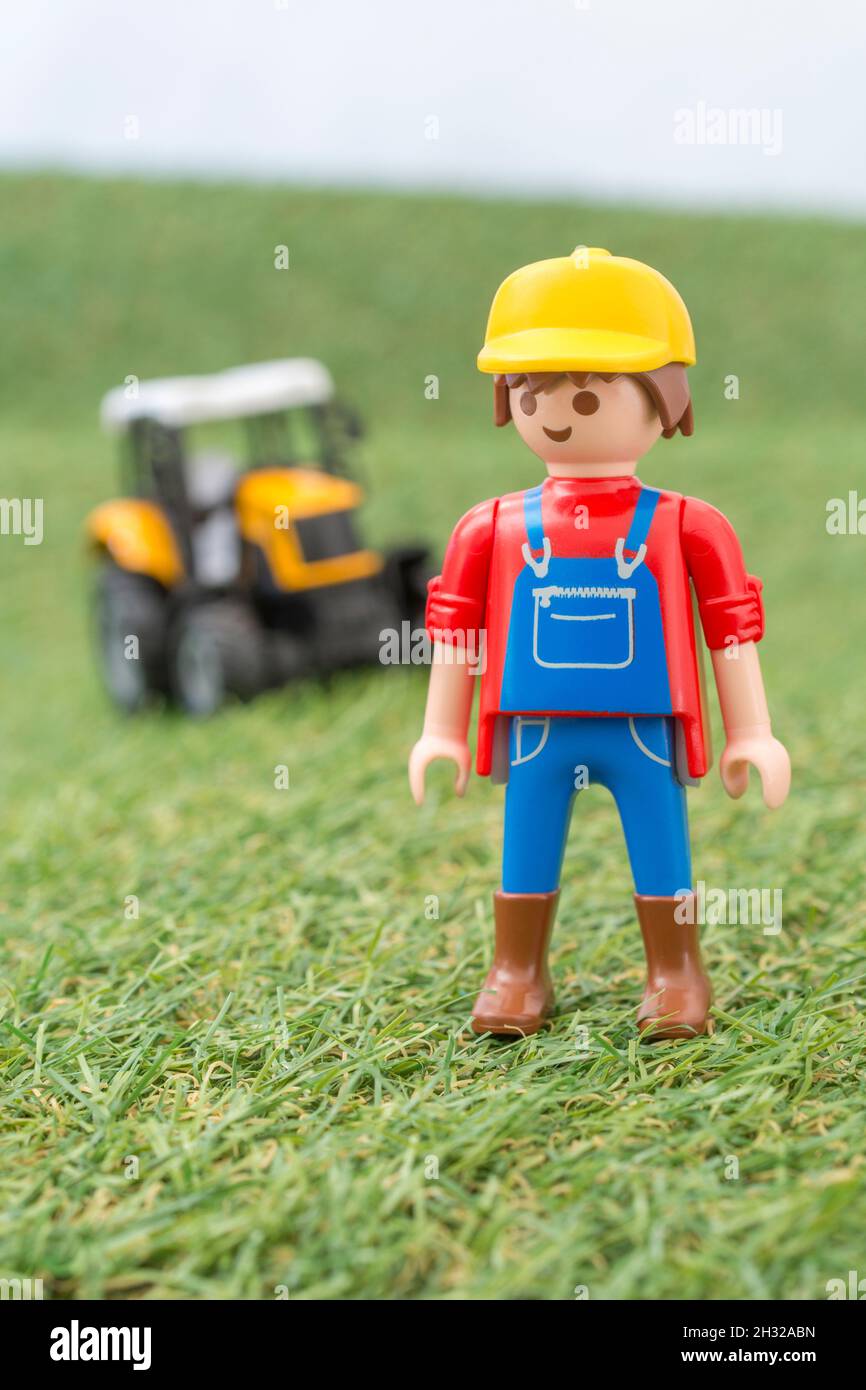 Small toy tractor on faux / fake grass with toy Playmobil farmer figure ...