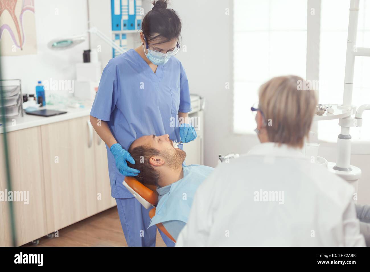 Medical nurse making professional teeth cleaning to man patient during ...