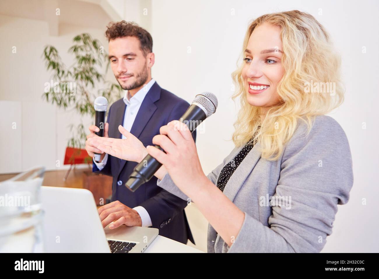 Two young business people with a microphone during a lecture and a ...