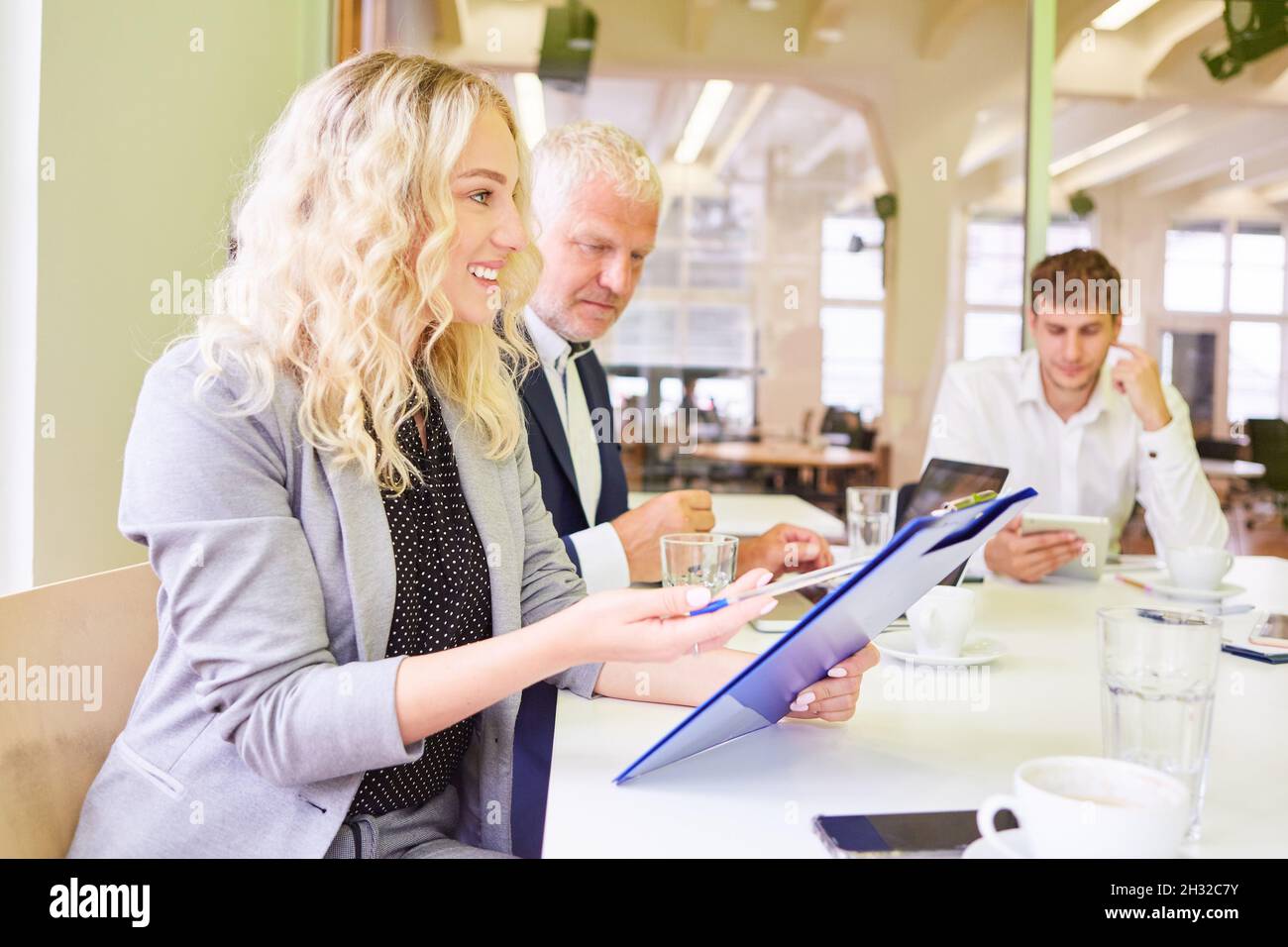 Young business woman as a trainee with clipboard in meeting during ...