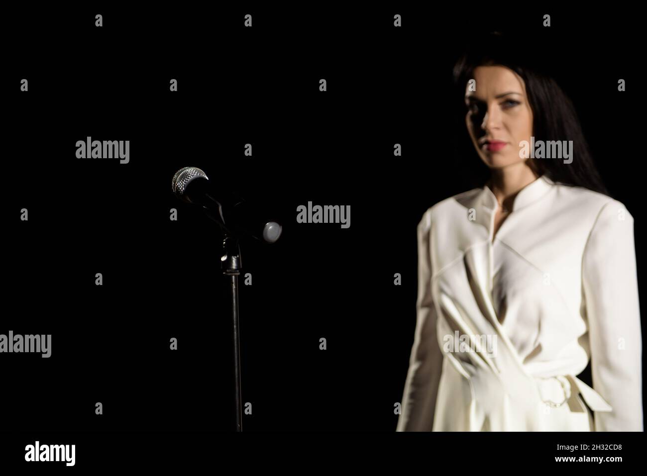 Back view of a singer with microphone singing a song on stage in white ...