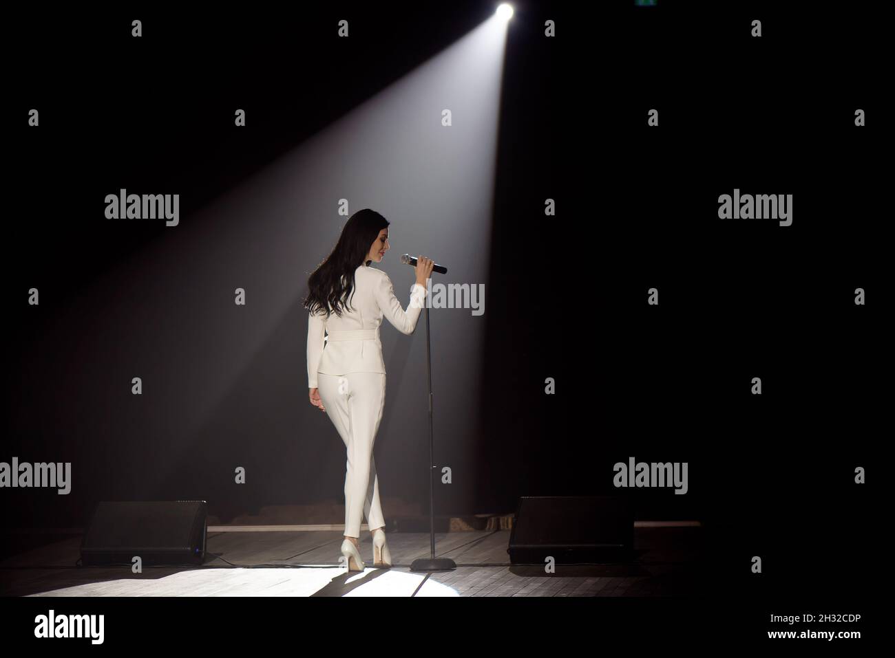 Singer on stage in a beam of white light Stock Photo - Alamy