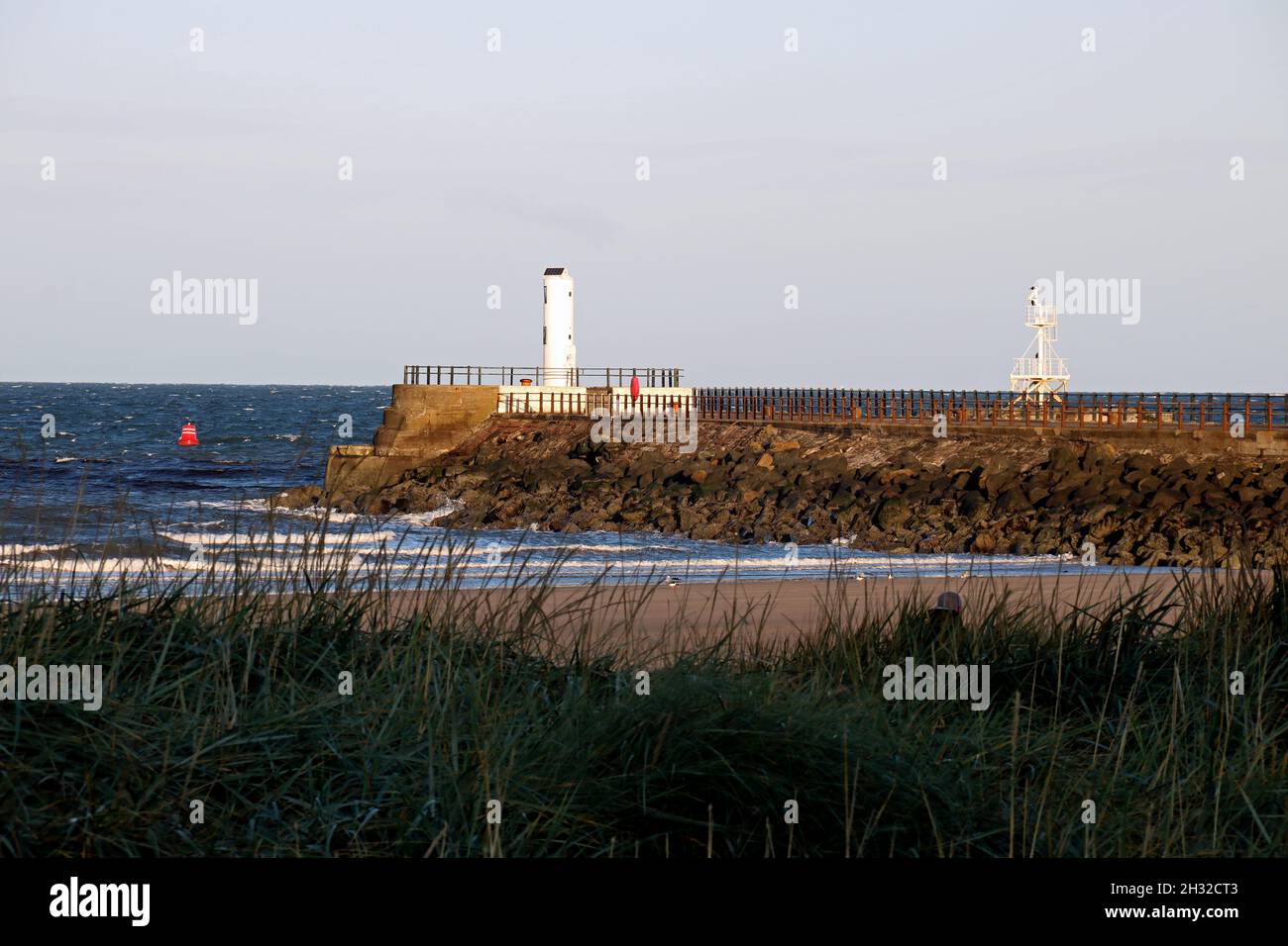 Coastal beach view with jetty and harbour light Stock Photo - Alamy