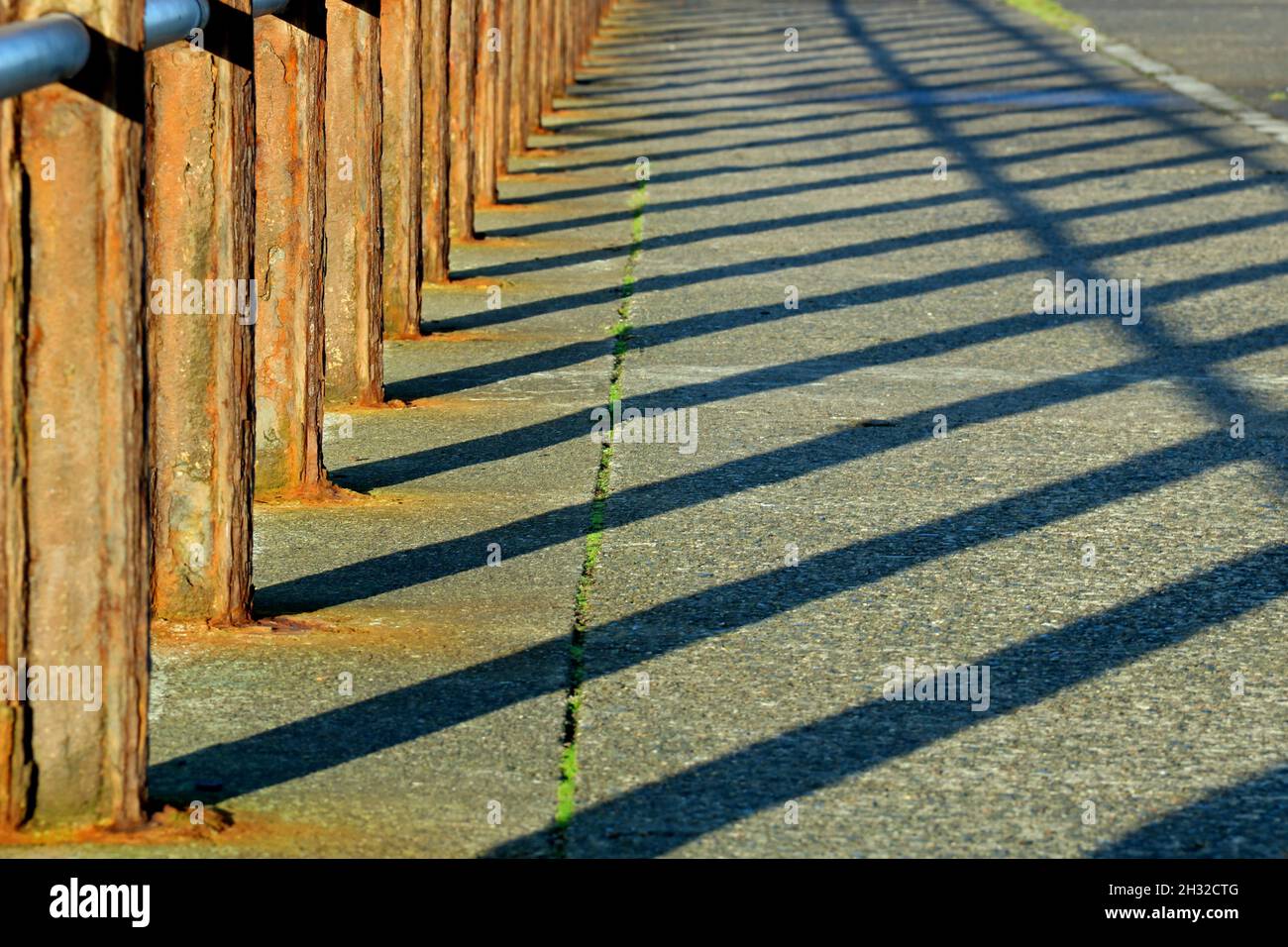Rusting safety barrier shadows at a coastal jetty location Stock Photo ...