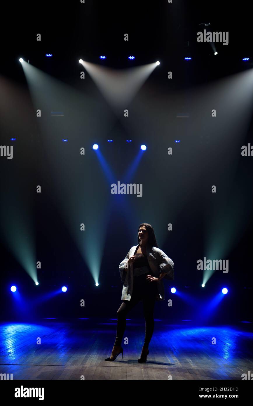 Singer perform on stage of nightclub in front of bright screen. Dark ...