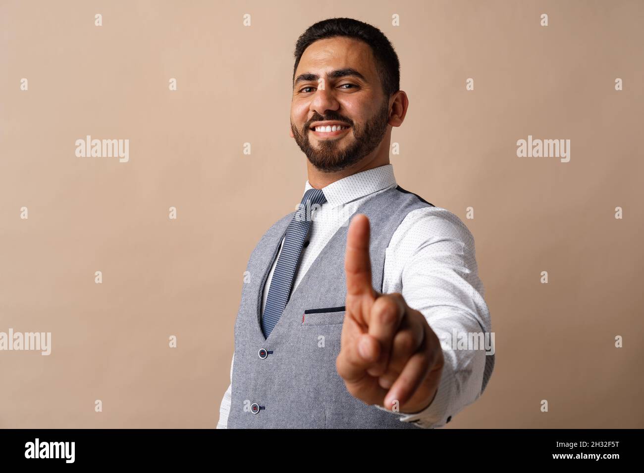 Young arabian businessman pointing finger to camera against beige ...