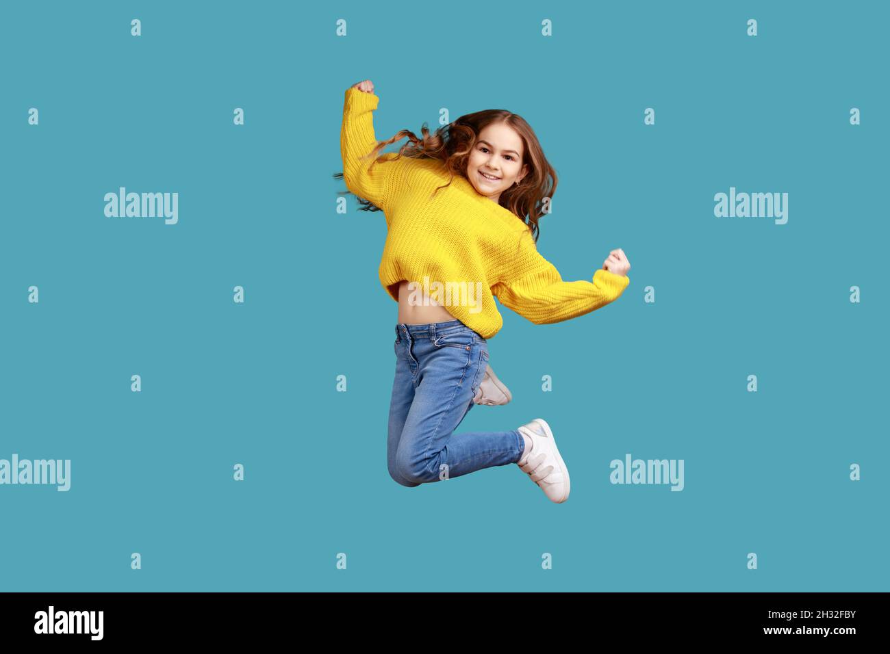 Full length portrait of little girl jumping up high, expressing ...