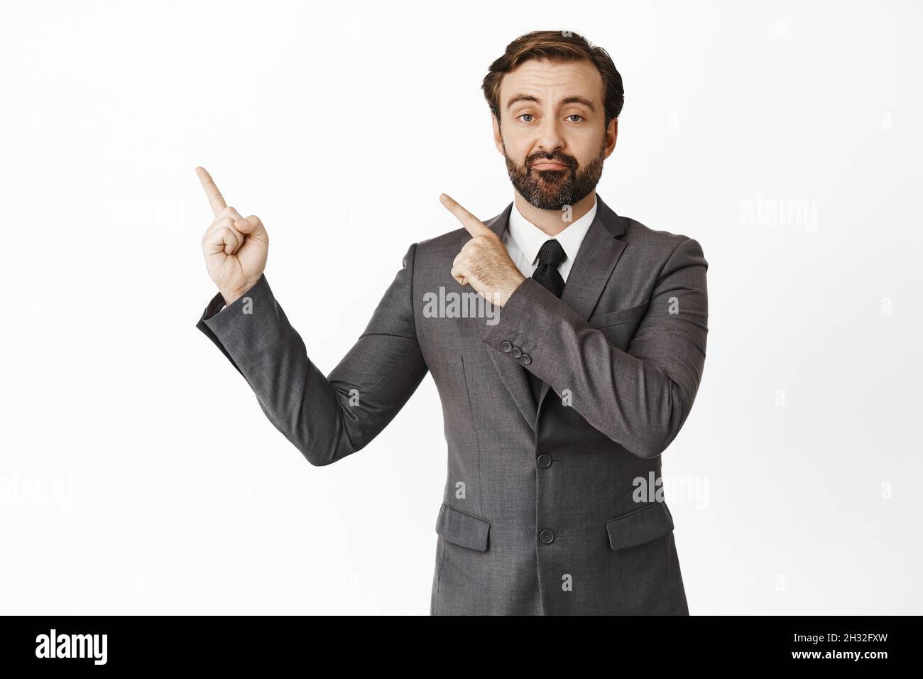 Disappointed male entrepreneur, pointing fingers at upper left corner ...