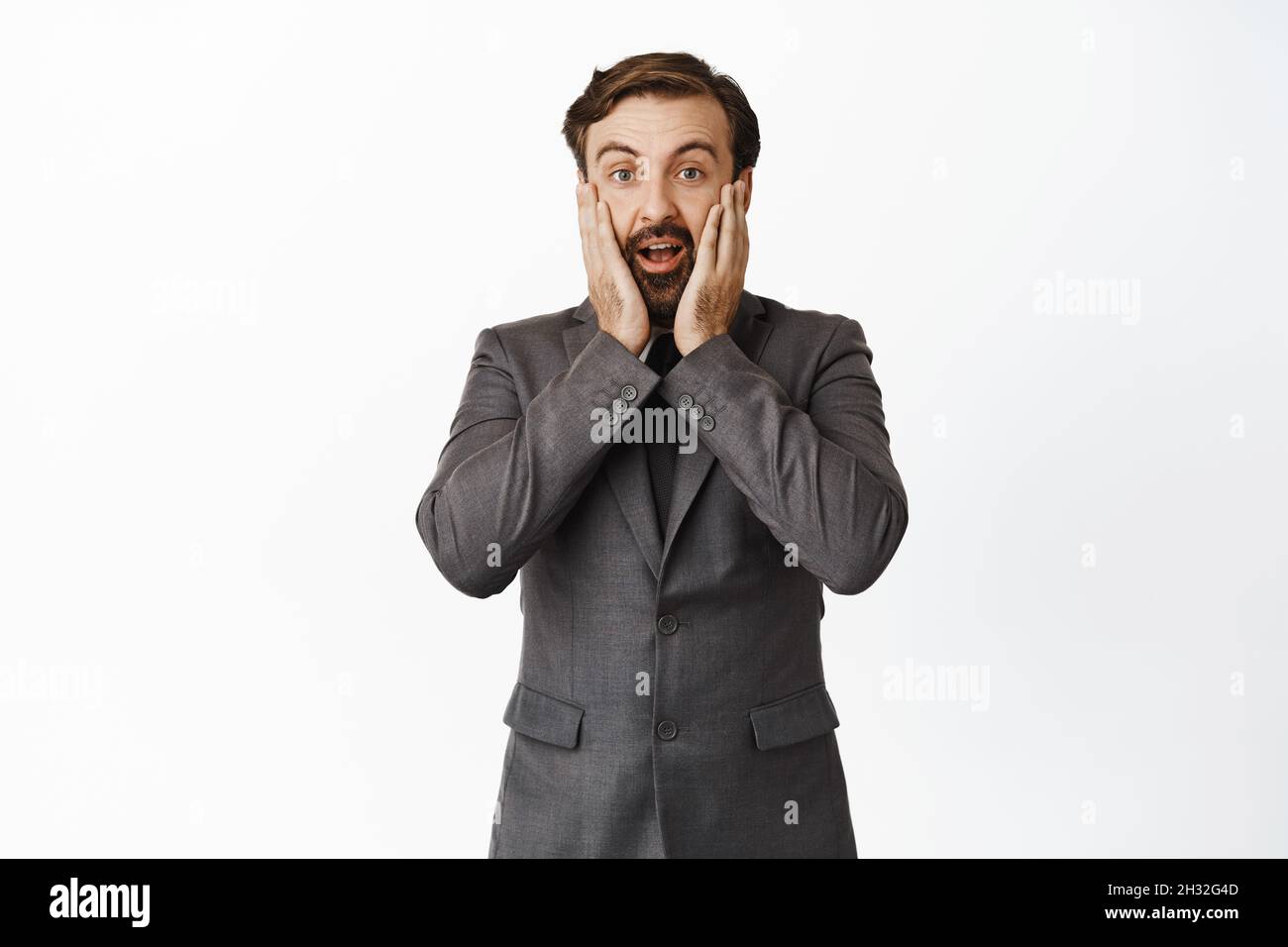 Portrait of surprised businessman touch his face, staring excited and ...