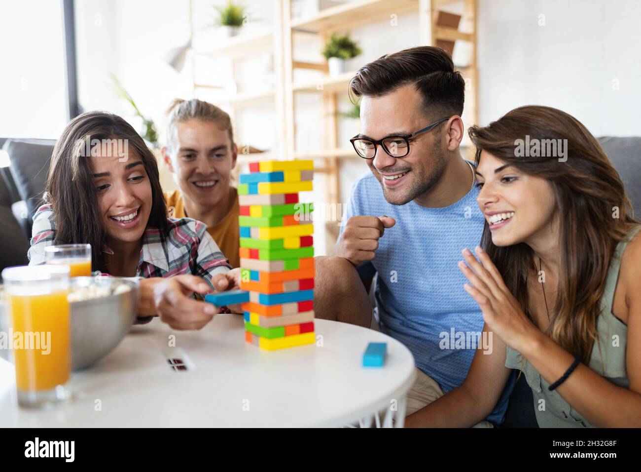 Group of young happy friends having fun playing wood board game Stock ...