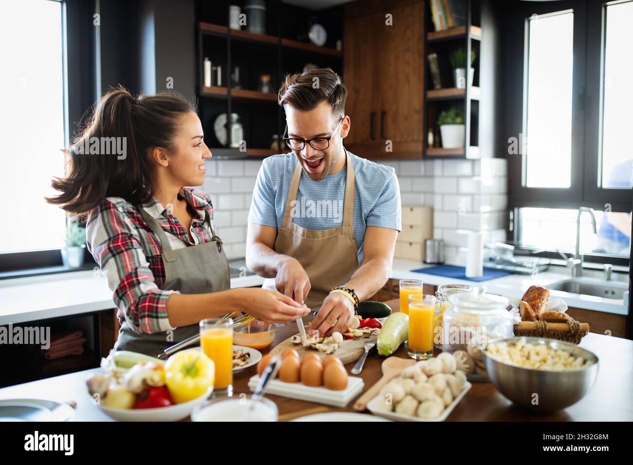 Beautiful couple is smiling while cooking together in the kitchen Stock ...