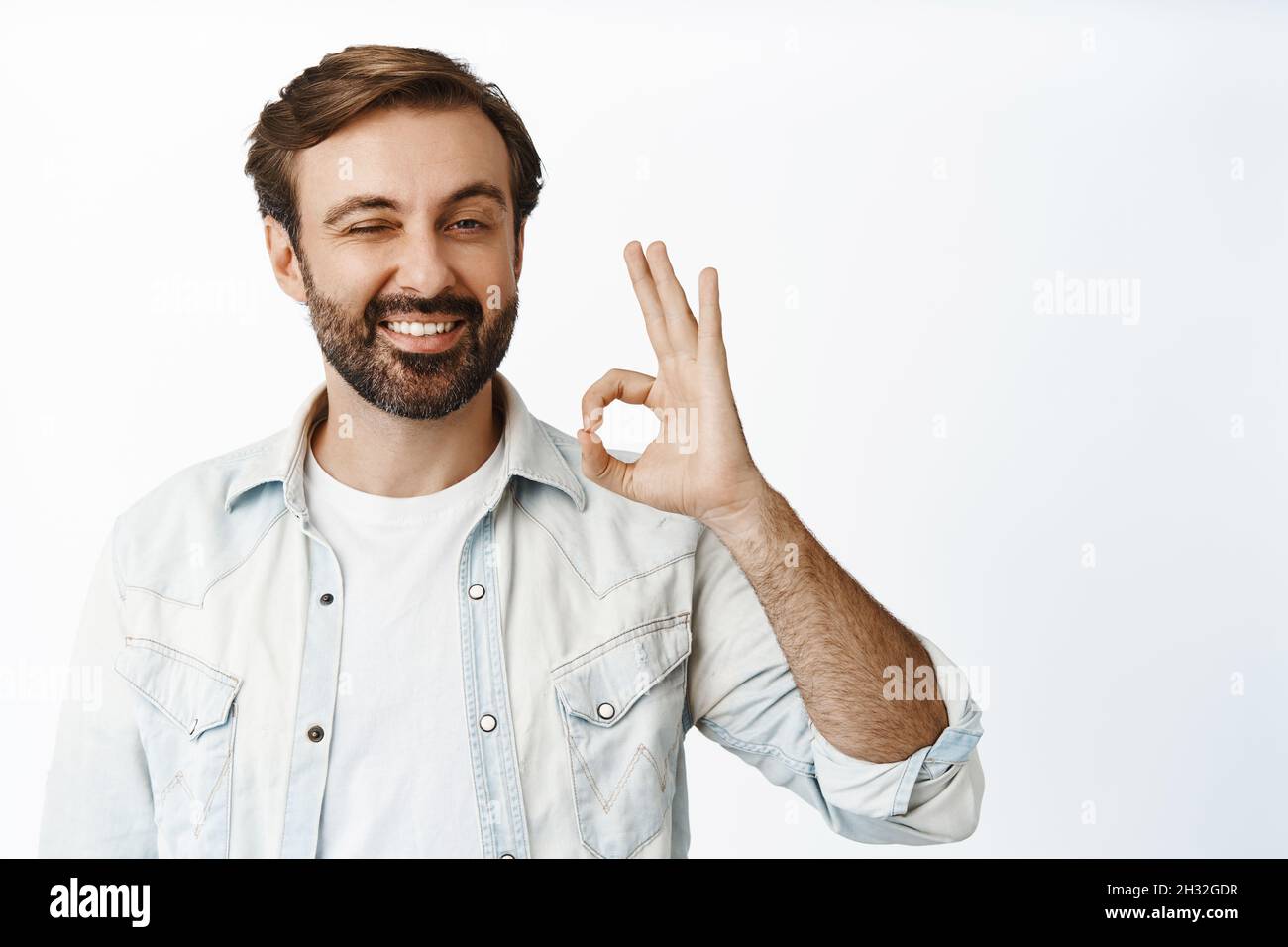 Very well. Smiling handsome man shows okay sign and winks, approves ...