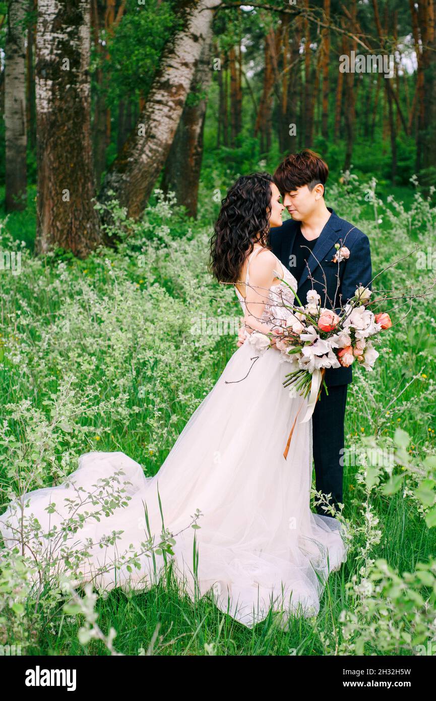 International couple. Wedding day. Young happy newlyweds in fresh green ...