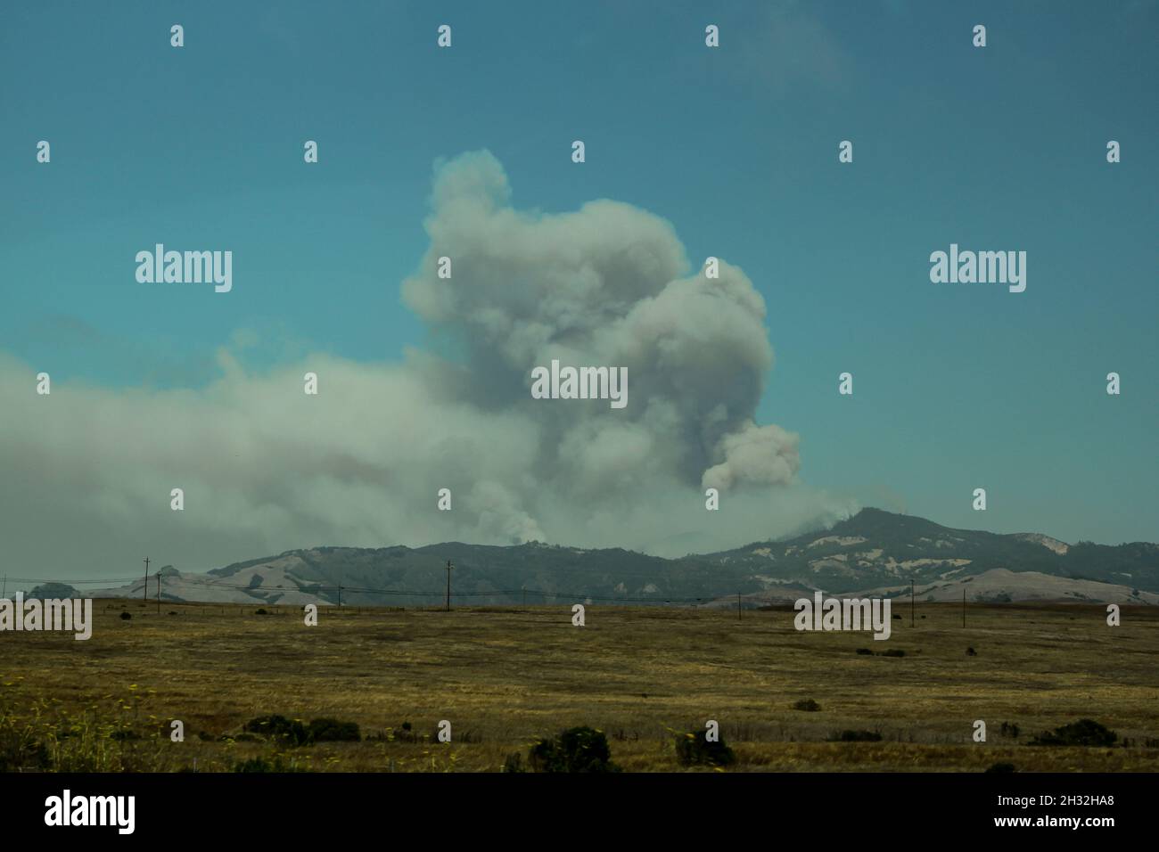 Landscape with stunning fire smoke clouds on a blue sky over land with ...