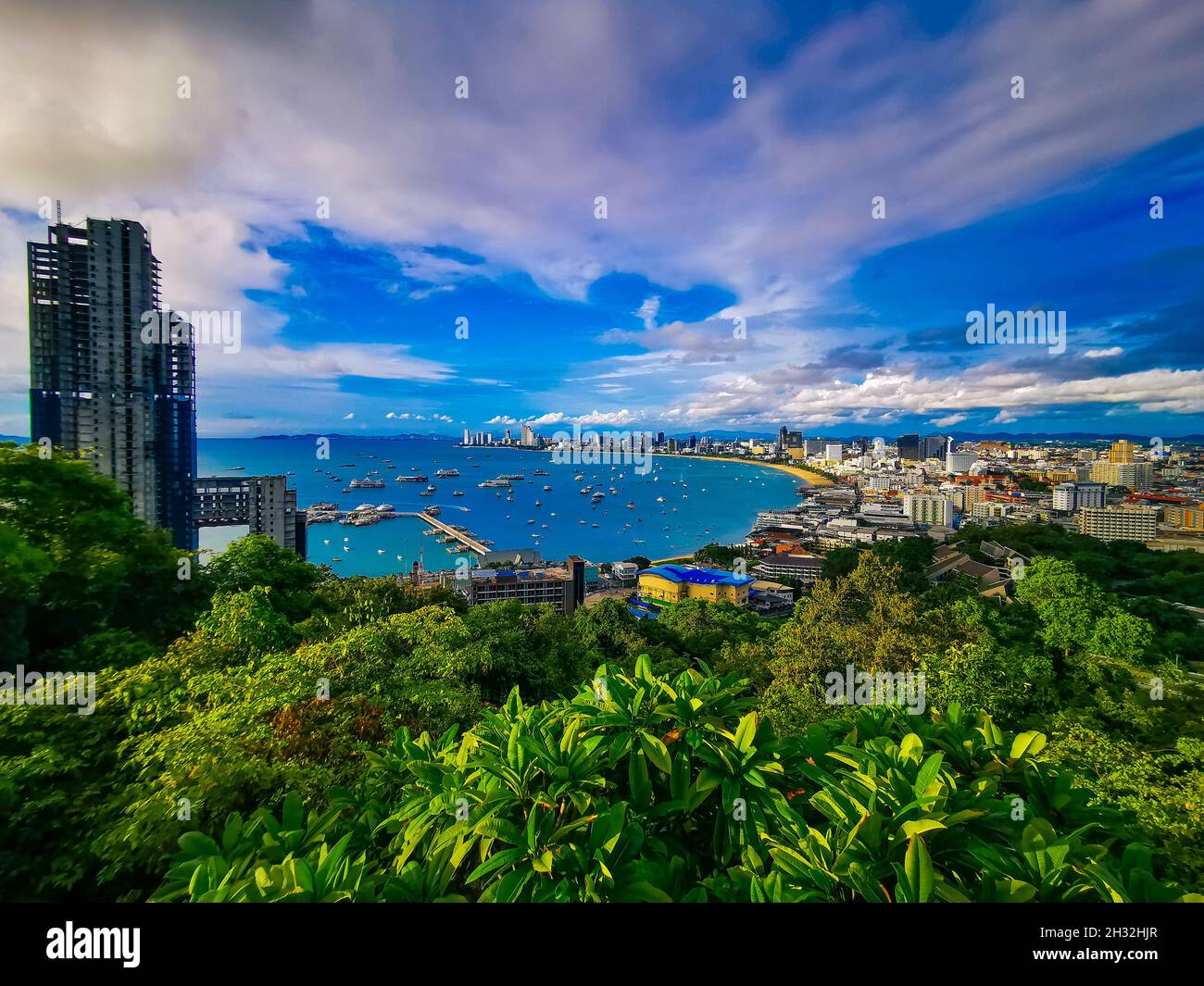 Cityscape view with dense greenery on the coast of the sea with a boat ...